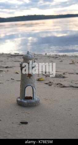 A vertical of a small lighthouse isolated on a green rocky mountain ...