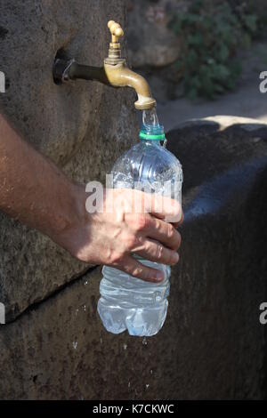Detail of an arm while filling water in a plastic bottle at the ...