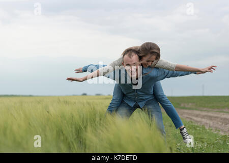 Couple enjoying piggyback ride with arms outstretched. Portrait of ...