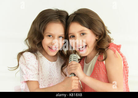 Cute little girl with microphone singing on light blue background Stock ...