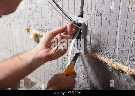 An electrician installing an electrical utility box into insulated ...