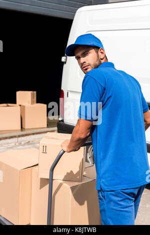 delivery man driving cart with boxes Stock Photo - Alamy
