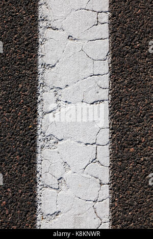 Urban road surface with cracks, road marking line and footprint, close ...