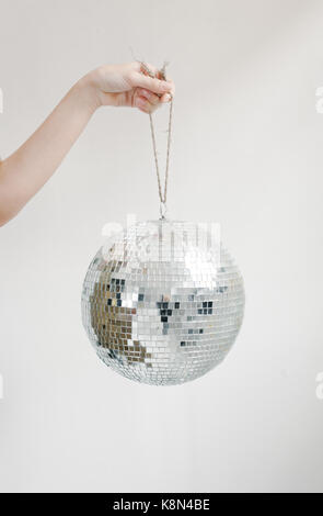 Woman holding disco ball on blue background Stock Photo - Alamy