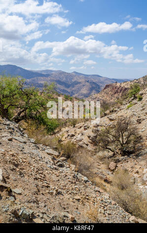 A beautiful view of a dry hillside with rocky mountains and fluffy ...