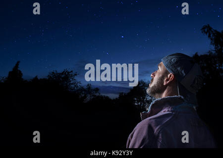 A Man looking towards stars in the night sky Stock Photo - Alamy