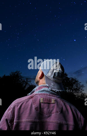 A Man looking towards stars in the night sky Stock Photo - Alamy