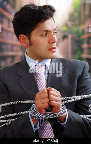 Businessman trapped in a chair with rope, with a black tape in his ...