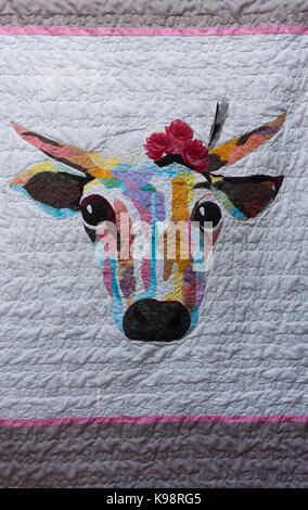 A brown and white cow with horns and yellow ear tags stands in a grassy ...
