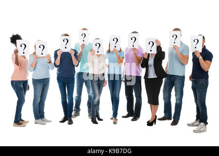Full length of business team hiding faces with question mark signs ...
