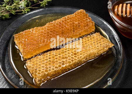 Honey and honeycomb on black dish Stock Photo - Alamy