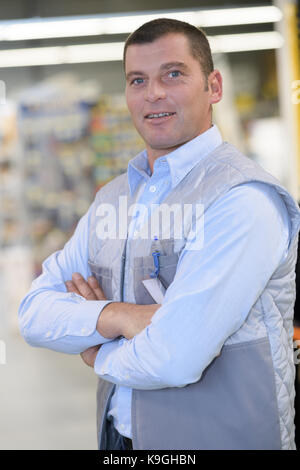 handsome hardware store salesman standing next to fasteners shelf Stock ...