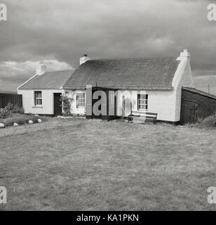 traditional irish stone cottage with slate roof with woman driving ...