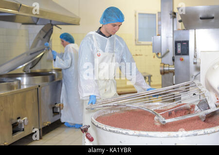 Factory worker watching over vat of food Stock Photo - Alamy