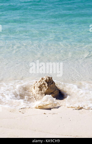 Sandcastle on the beach being washed away by the waves - concept of ...
