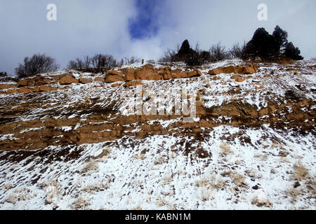 A rock cut and trees covered with snow alongside a highway, make a ...