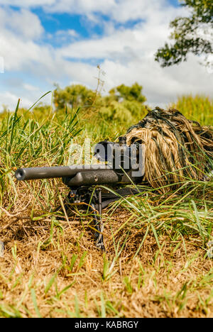 Police SWAT sniper in a ghillie suit looking through a rifle scope ...