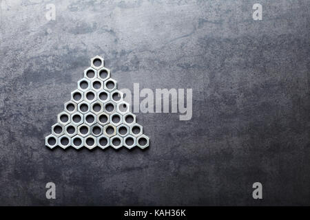 Triangle from screw nuts on metal texture background Stock Photo - Alamy
