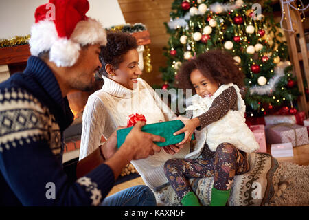Smiling mother gives her daughter a christmas present. Happy family ...