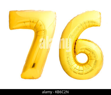 Gold foil balloon number number 76 on a background of blue velvet ...