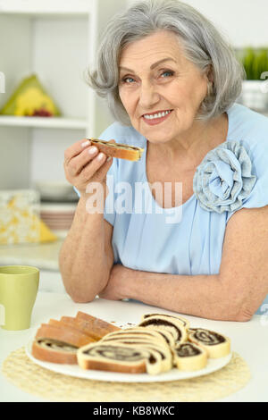 Mature woman holding plate with cookies on white background Stock Photo ...
