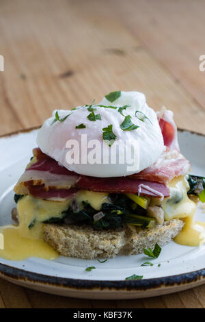 rustic tasty eggs benedict on plate on wooden table Stock Photo - Alamy