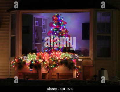 Window with decorated glowing christmas tree inside a house and bright ...