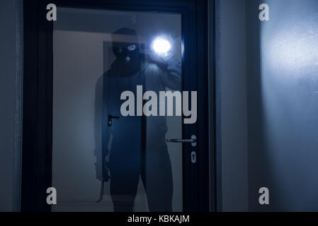 Thief With Flashlight Trying To Break Office Door Stock Photo - Alamy