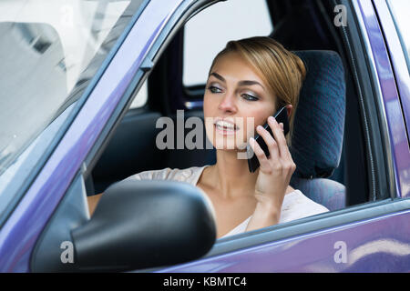 Woman Using Mobile Phone While Driving Car Stock Photo - Alamy