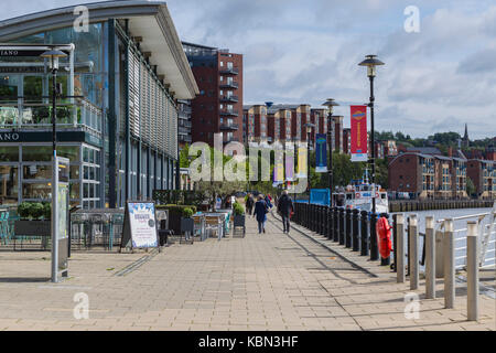 People walking along Newcastle quayside with the Tyne bridges in the ...