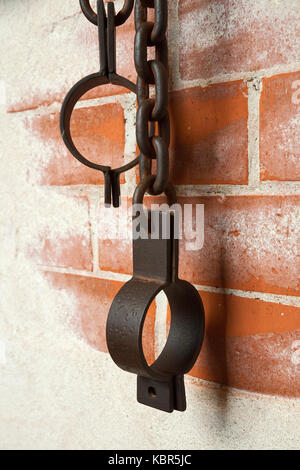 Old rusty shackles with chain on wall in prison Stock Photo - Alamy