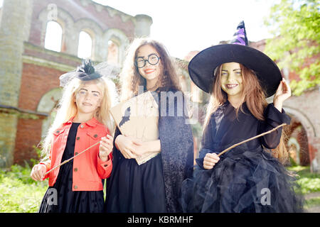 Happy Halloween! Three cute little laughing girls in witches costumes ...