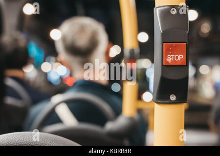 Shallow focus of a red stop button seen inside a public bus. Used to ...