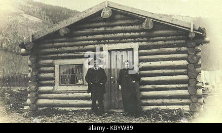 Mr Antone and woman in front of log cabin, Birch Creek, Yukon territory ...
