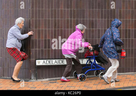 Woman struggling against strong wind, holding on to leaning tree, wind ...