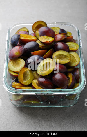 Halves of fresh ripe plums in glass bowl Stock Photo - Alamy