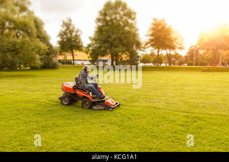 A man driving a lawn mower, a tractor working on the land Stock Photo ...