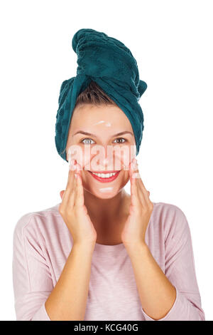Young woman wearing a shower towel using face cream over yellow ...