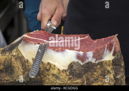 Slicing dry-cured ham prosciutto. Professional cutter carving slices ...