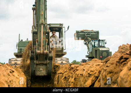 U.S. Army Sgt. Jim Miller operates a heavy equipment excavator to dig a ...