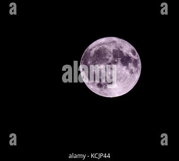 A bright full moon rises above Governor's Island in New York harbor on ...