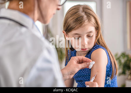 Pediatrics female doctor giving a young girl a vaccine shot in the leg ...