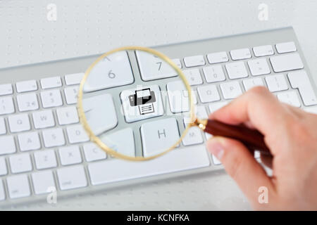 Close-up of hand looking at printer key through magnifying glass Stock ...
