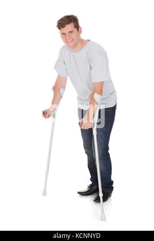 Young handsome man with crutches in conflicting priorities concept ...