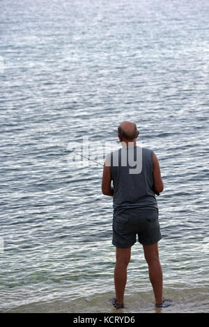 Fisherman standing on the beach and trying to catch some fish Stock ...