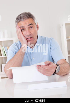 Horrified old man reading a document with an aghast expression Stock ...