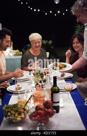 Group of senior people sitting at dining table having dinner and ...