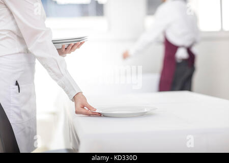 Waiter and waitress laying the table Stock Photo - Alamy