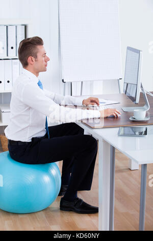 Businessman Sitting Comfortably On Fitness Ball And Using Computer In ...