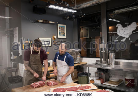 Two young men in butcher s shop with raw meat hanging in village near ...